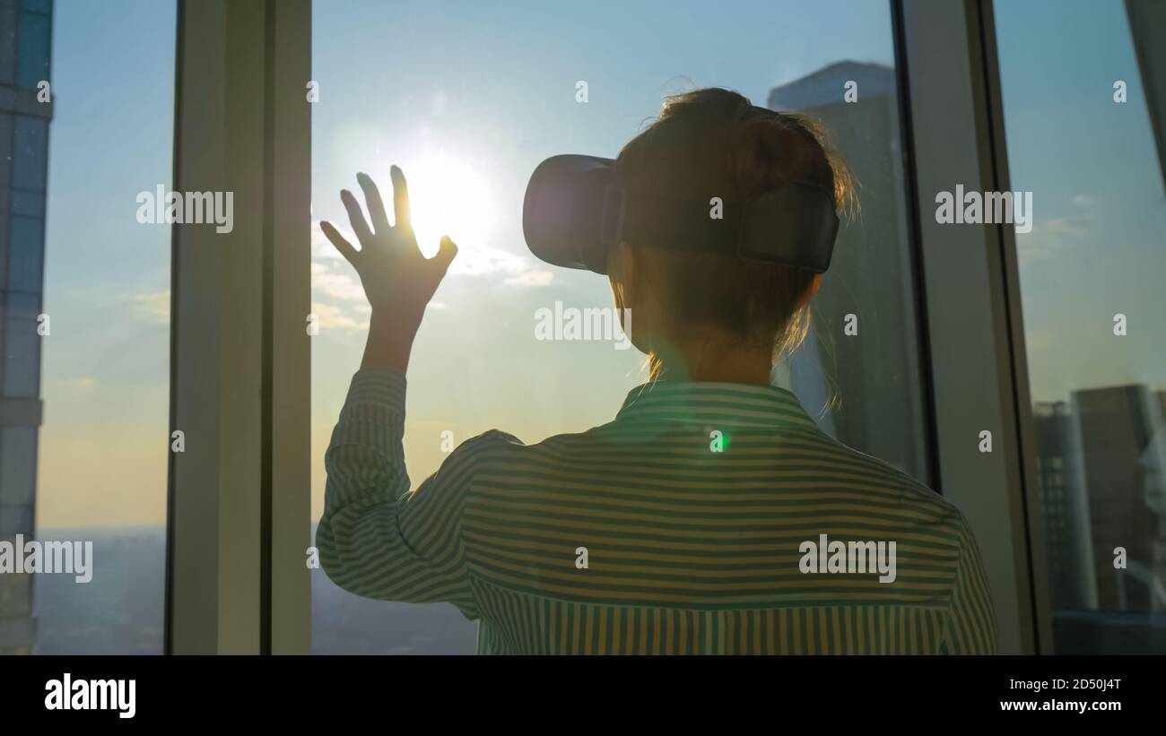 Woman using virtual reality headset and moving hand against view on ...