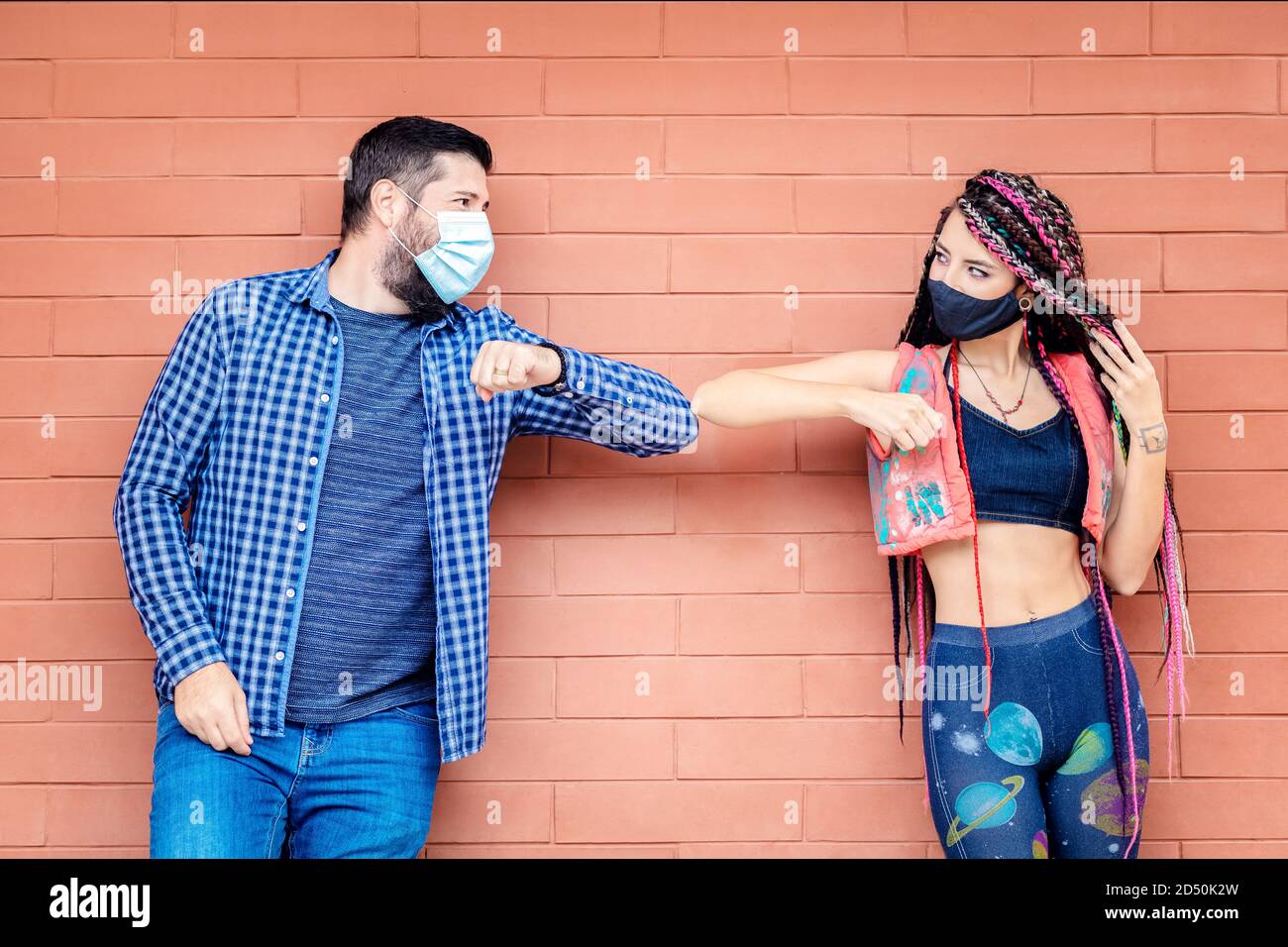 Happy friends wearing protective face mask while greeting by bumping ...