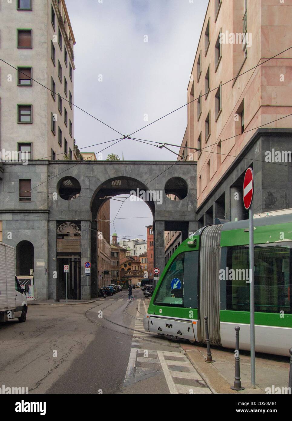 Green tram passes under an arch between two buildings in the narrow ...