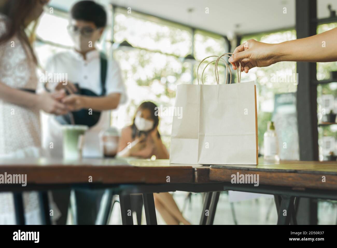 Hands giving eco friendly paper bag to customer in cafe Stock Photo - Alamy