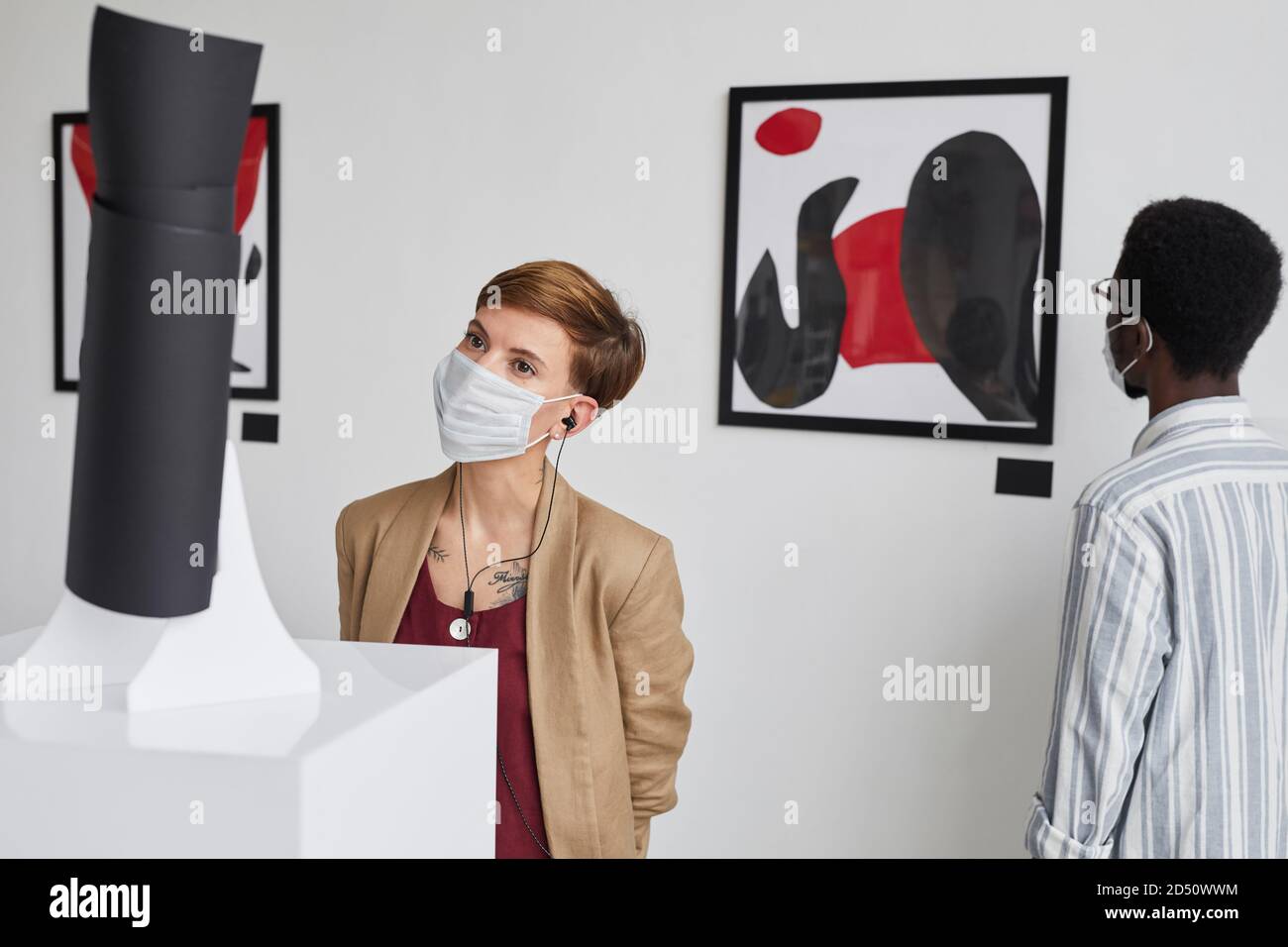 Portrait of two young people looking at paintings and sculptures while ...