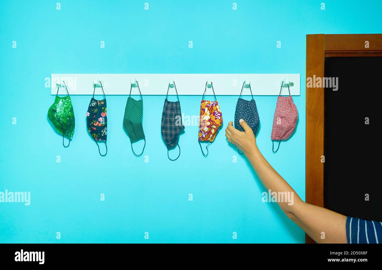 Arm of a person picking up a hygienic mask. Anti-Covid-19 masks hanging ...
