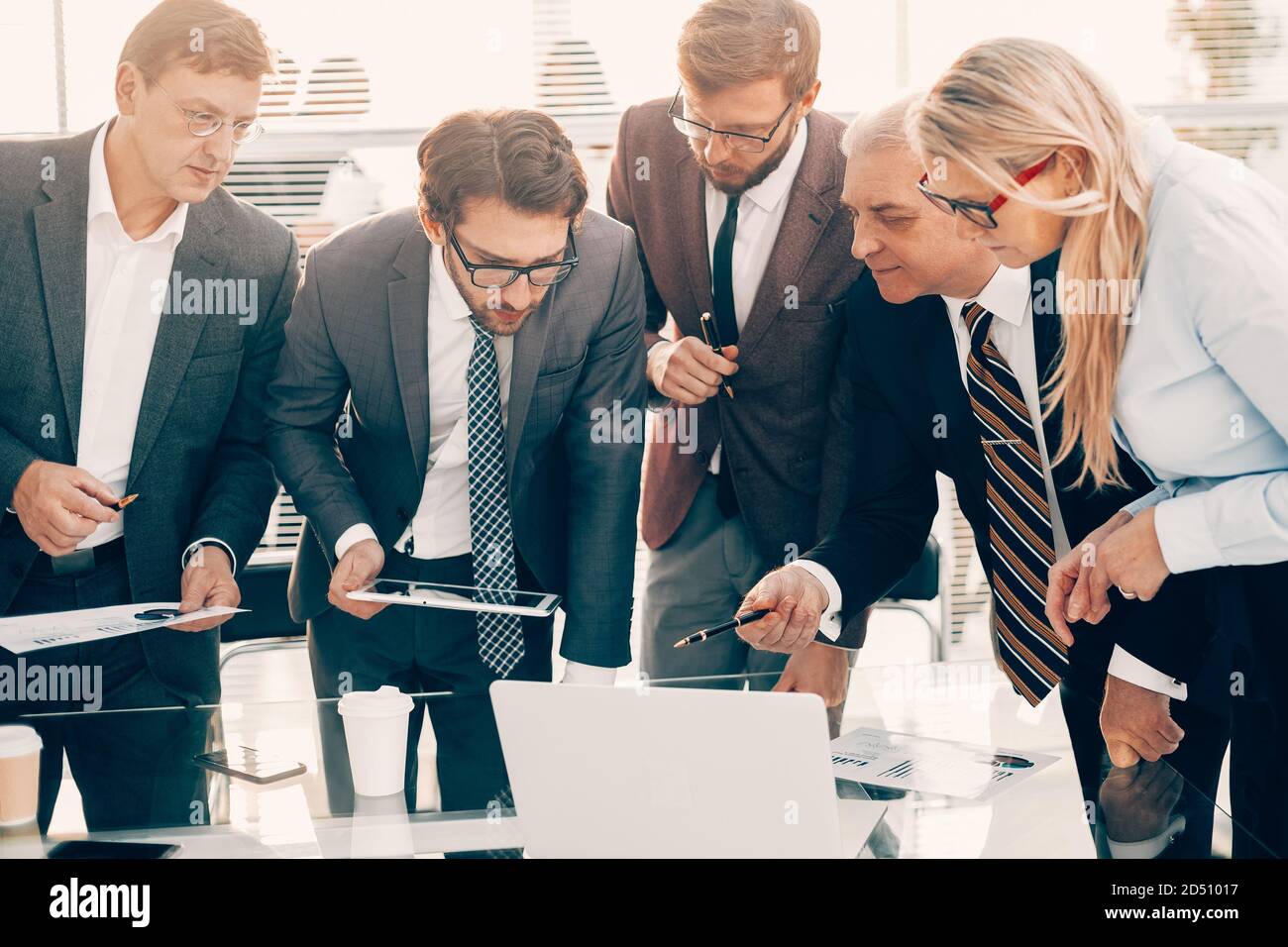 group of employees looking at the laptop screen with interest Stock ...