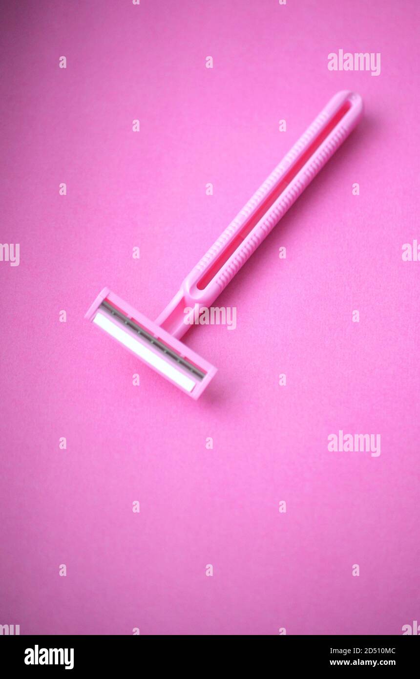 Isolated pink plastic female razor for single use on a same pink ...