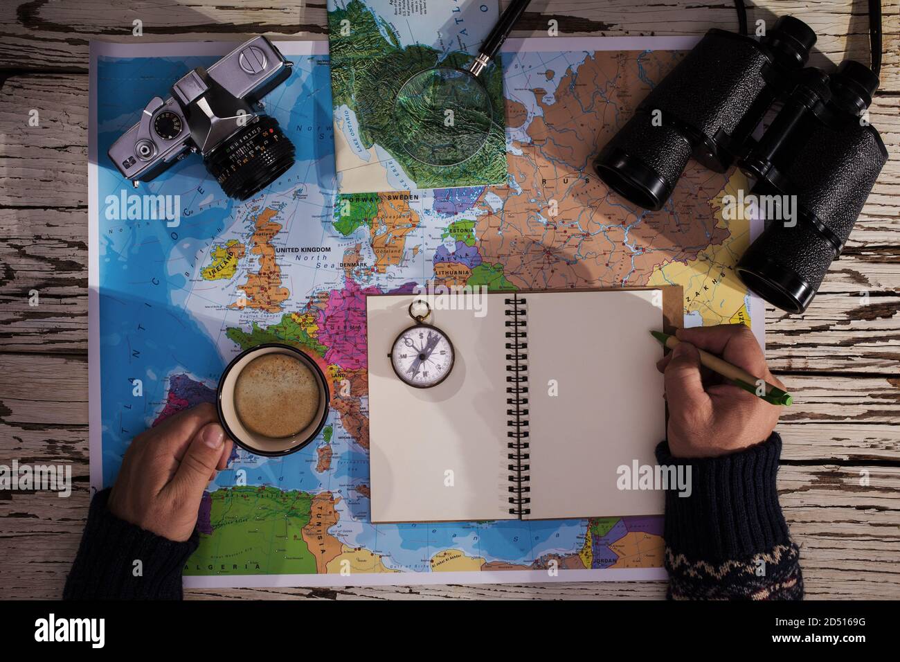 Flat lay of the travel planning concept. Top view of man hands wriìting on a diary, on the table ...