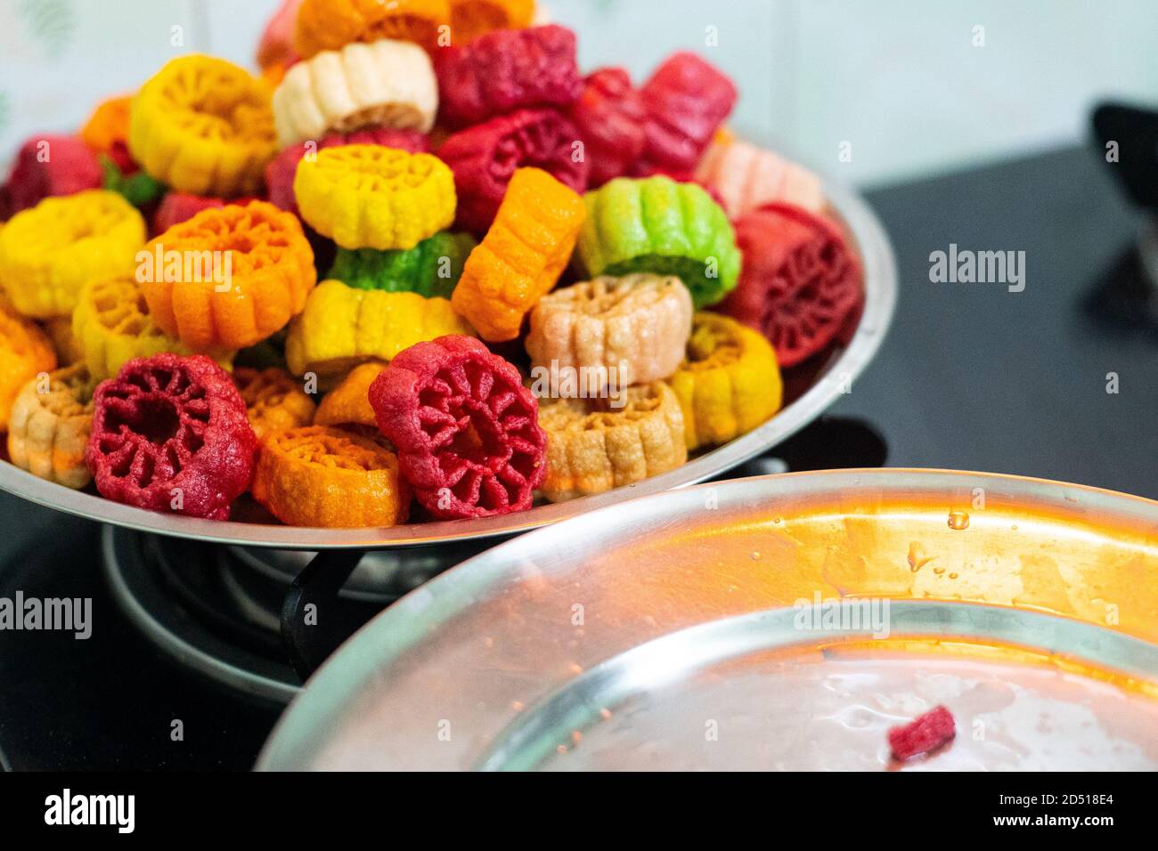 shot of colorful Fryums being deep fried in hot oil bubbling and ...