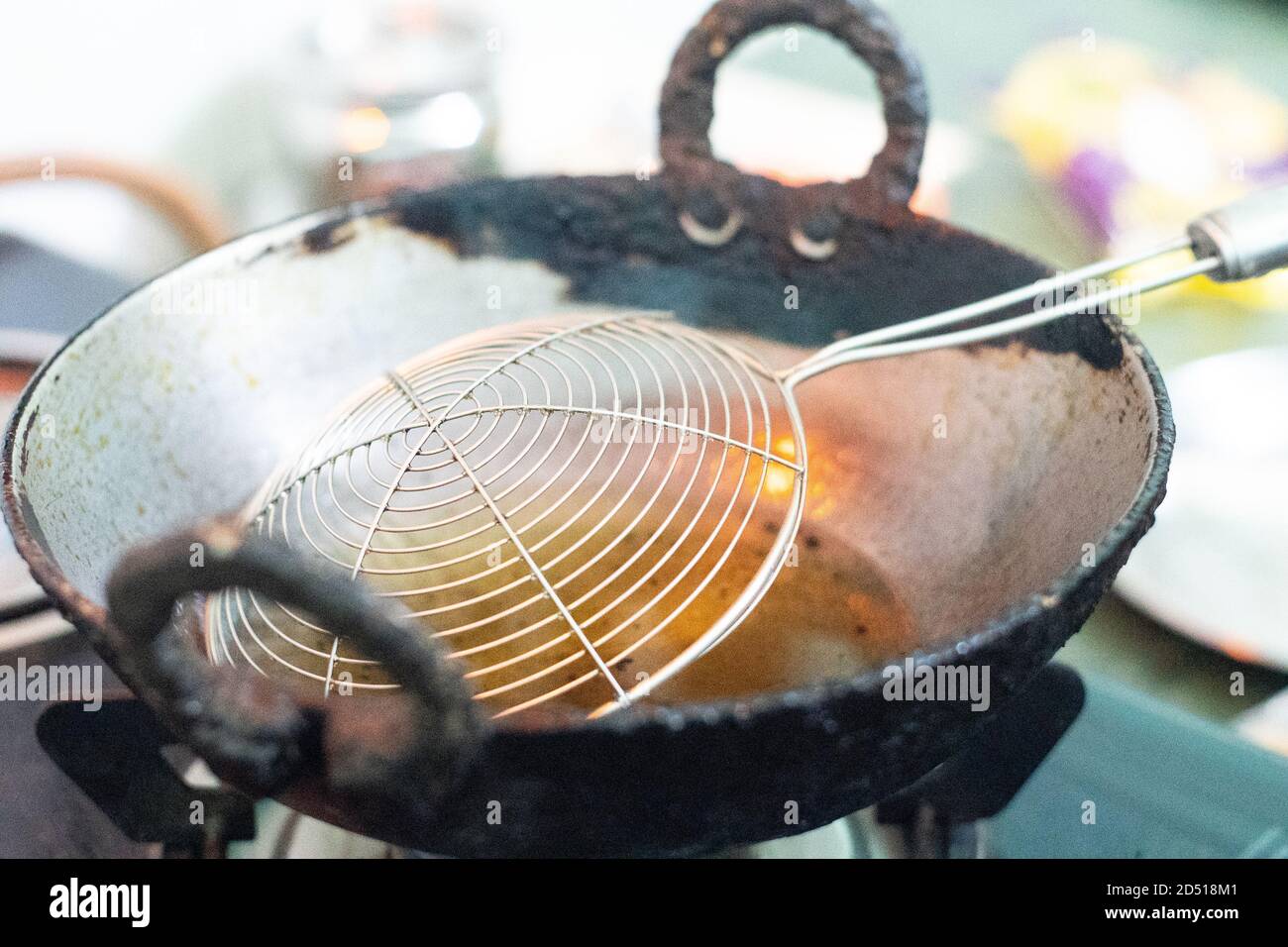 Empty old chipped deep frying pan with oil filled and a wire sieve ...
