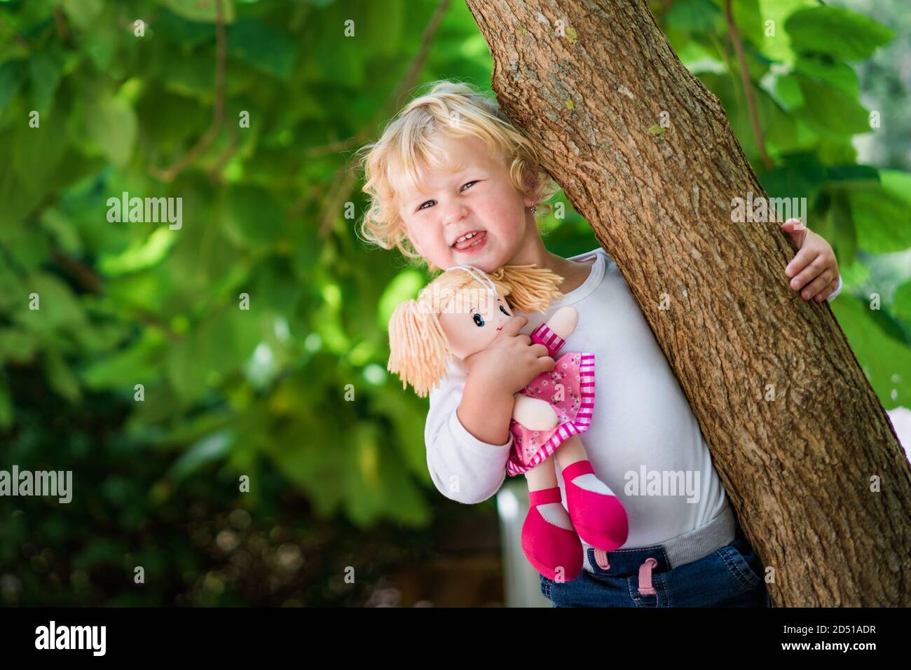 Little child standing next to tree Stock Photo - Alamy