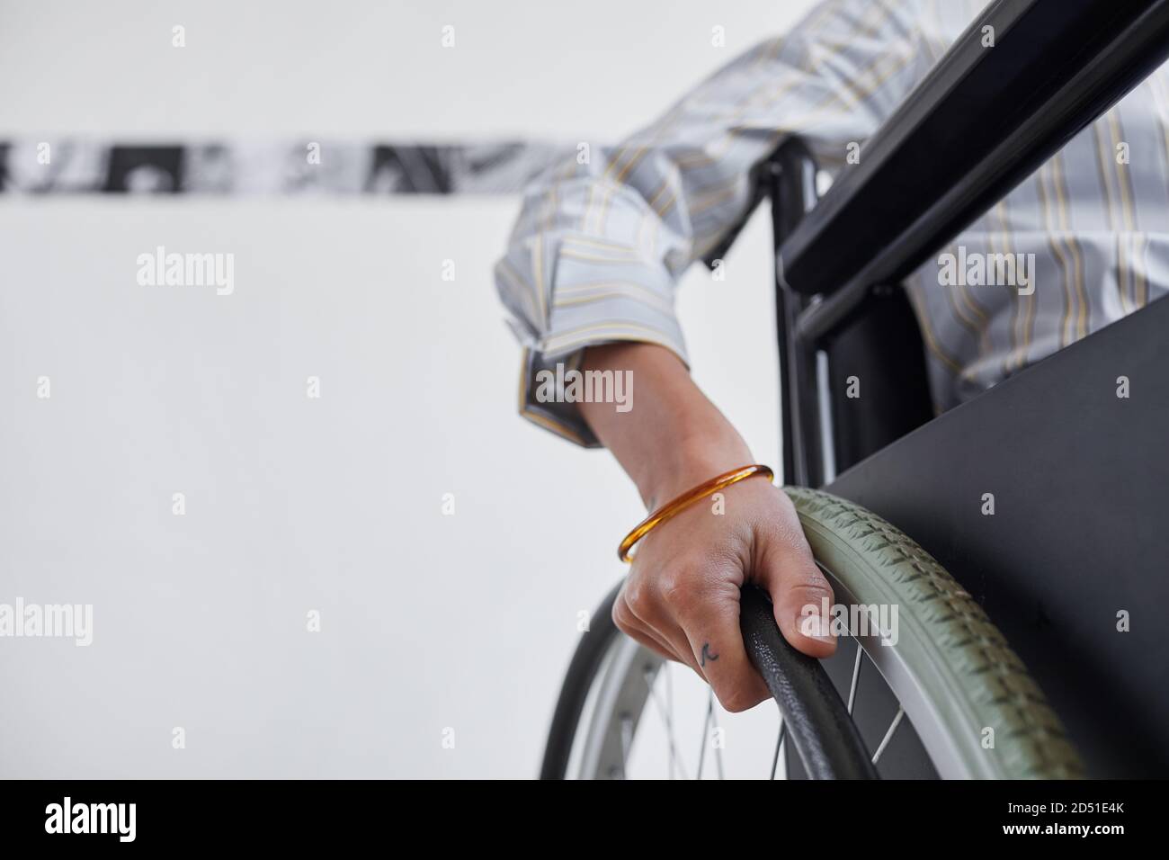 Close up of unrecognizable young woman pushing wheels of wheelchair ...