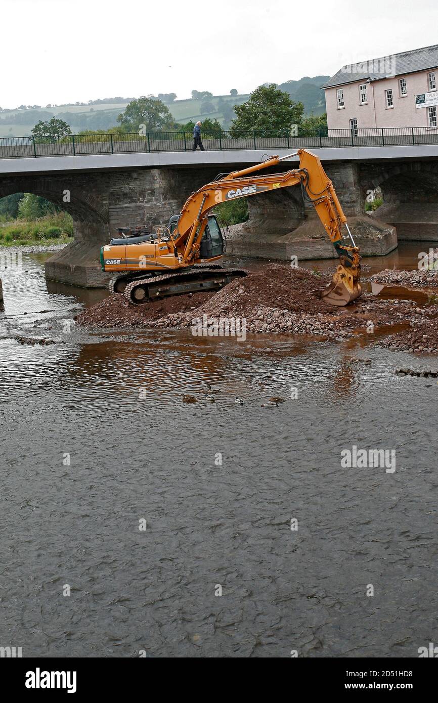 River Usk, Brecon, Powys, Wales. A heavy plant vehicle moves mud and ...