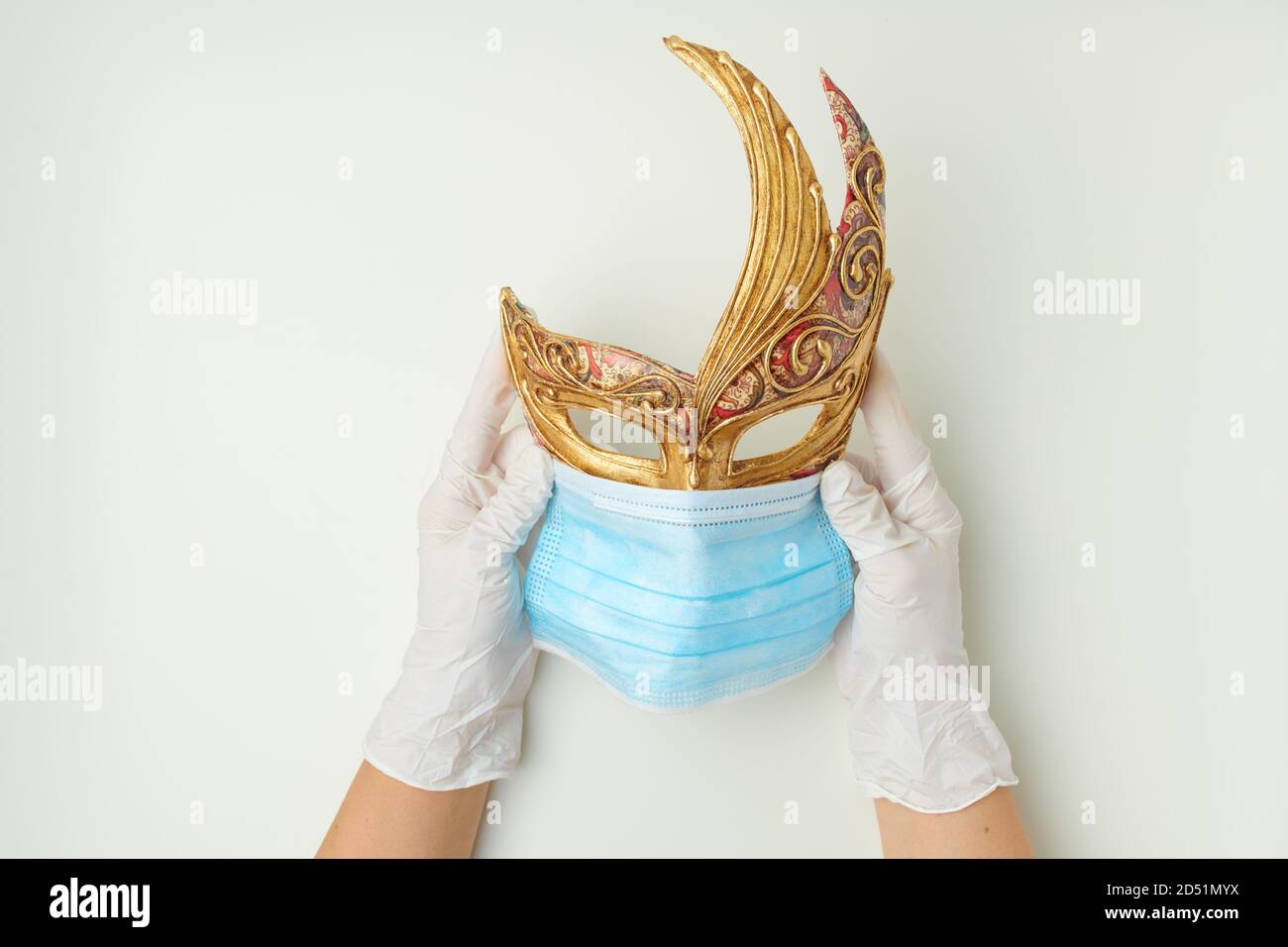 Upper view of woman hands in white rubber gloves holding venetian mask ...