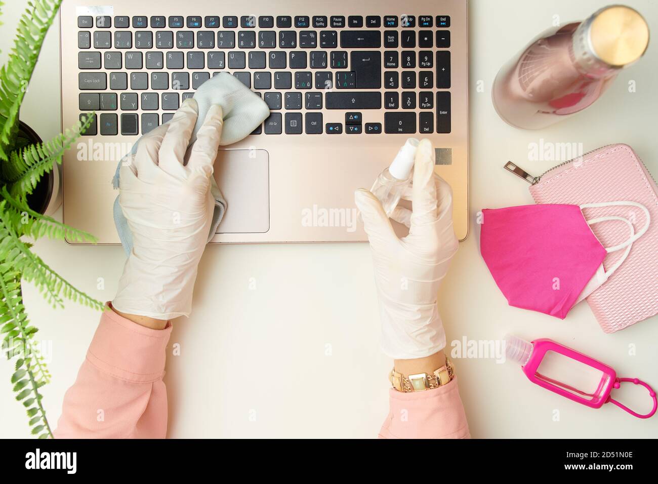 Upper view of female hands in white rubber gloves disinfecting laptop ...