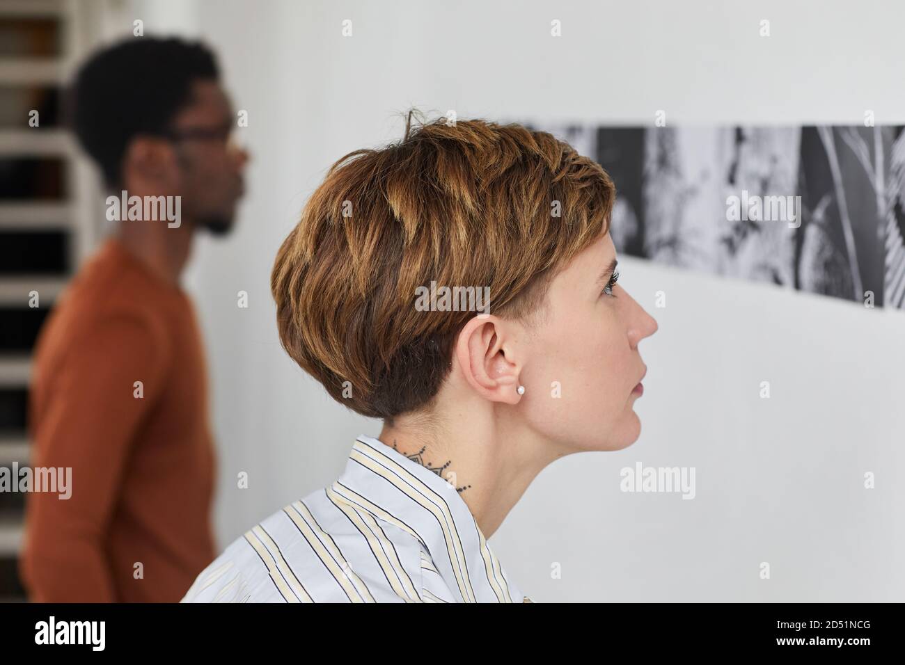 Close up side view portrait of modern young woman looking at paintings ...