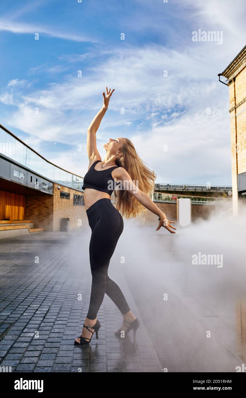 Beautiful woman dancer with long blond hair posing on city street ...
