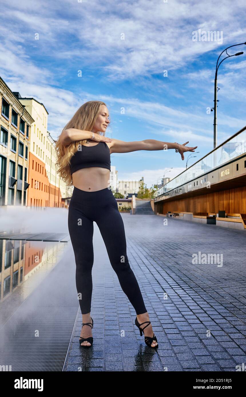Beautiful woman dancer with long blond hair posing on city street ...