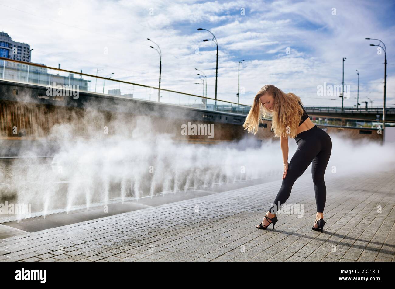 Beautiful woman dancer with long blond hair posing on city street ...
