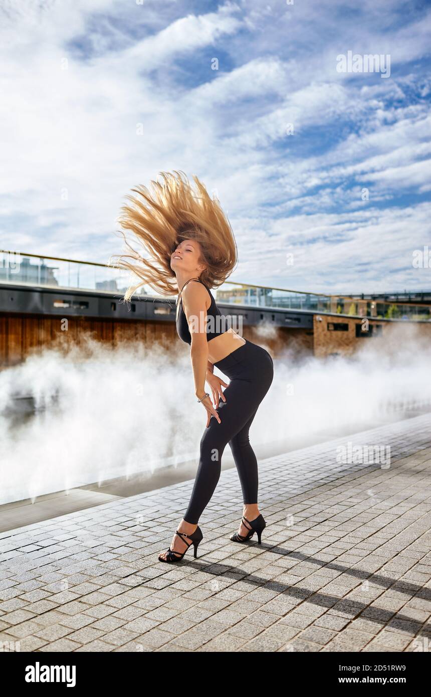 Beautiful woman dancer with long blond hair posing on city street ...