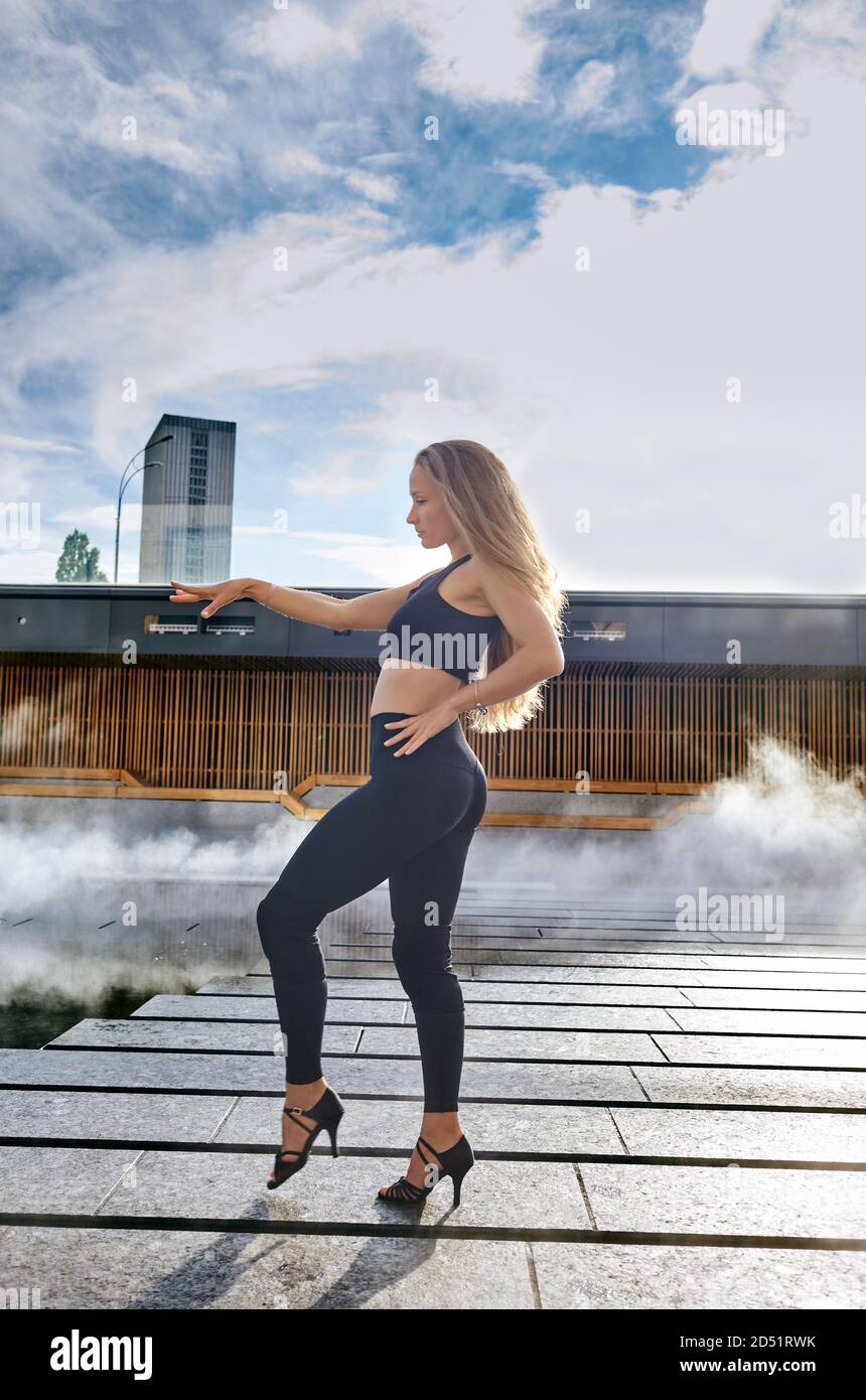Beautiful woman dancer with long blond hair posing on city street ...