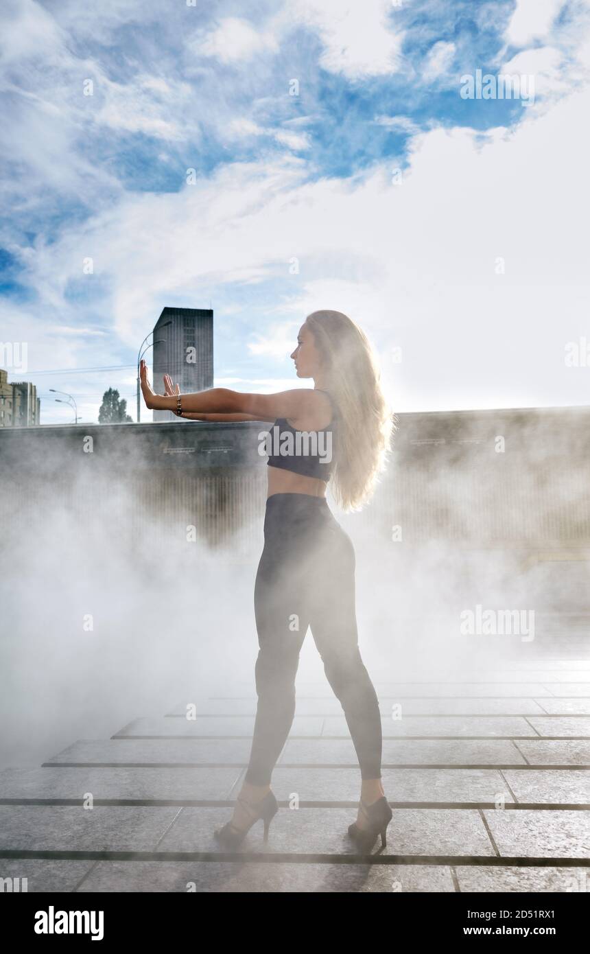 Beautiful woman dancer with long blond hair posing on city street ...