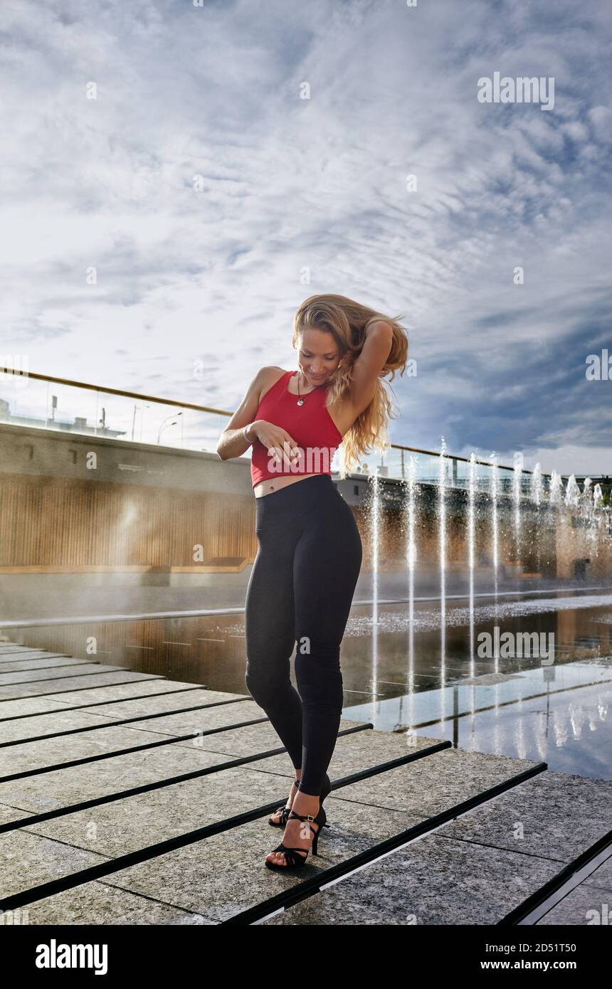 Beautiful woman dancer with long blond hair posing on city street ...