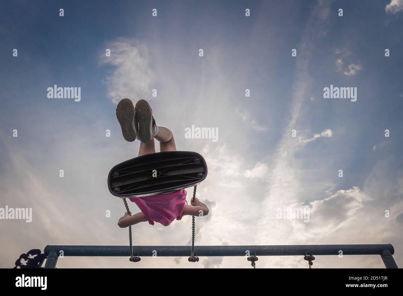 underneath angle of young girl swinging against blue sky Stock Photo - Alamy