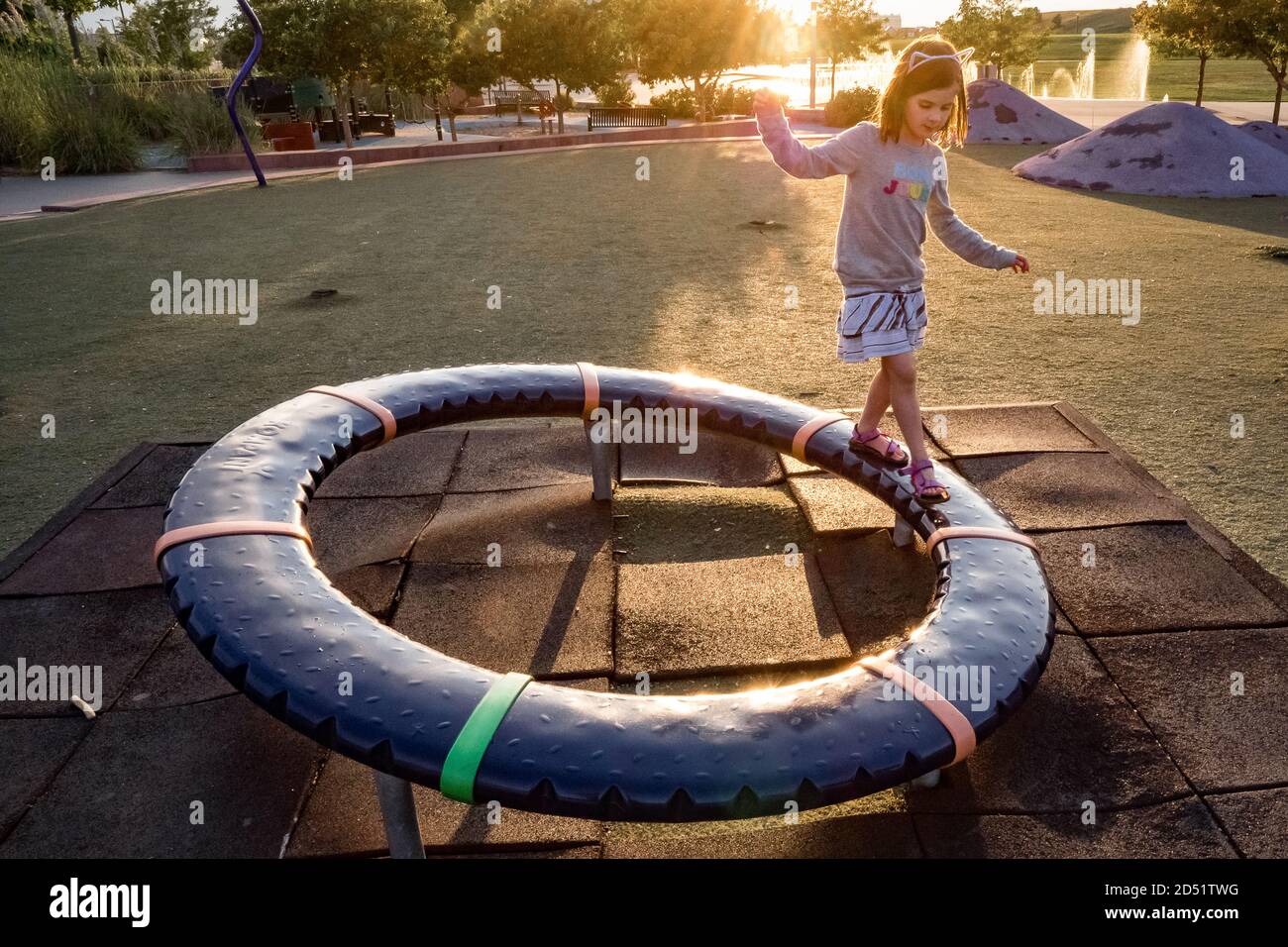 young girl balances while walking on circle structure at a playground ...