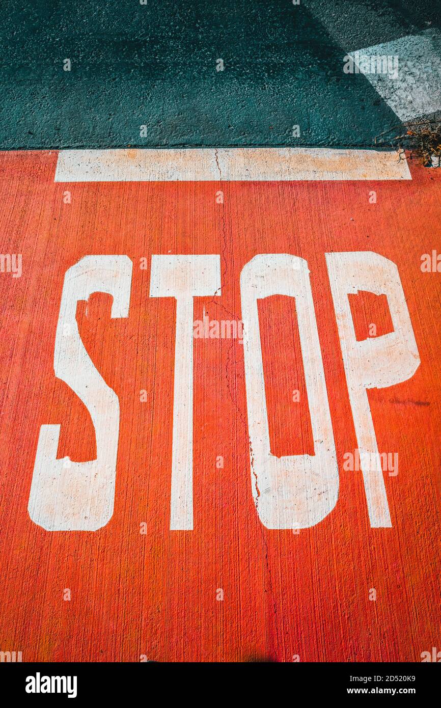 A stop sign painted on the rough red concrete floor, vertical copy ...