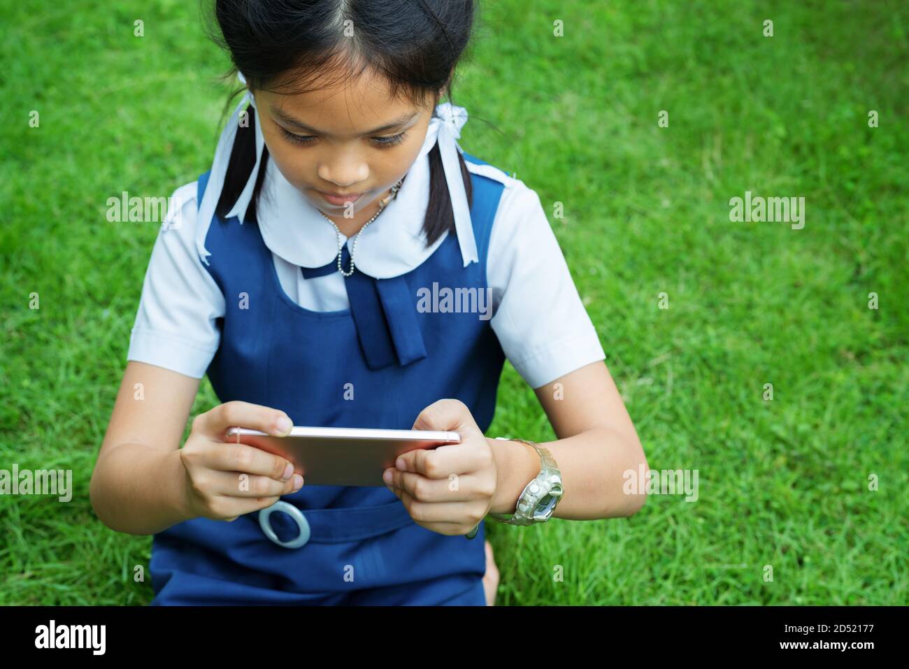 cute little girls playing internet with mobile smartphone on grass ...