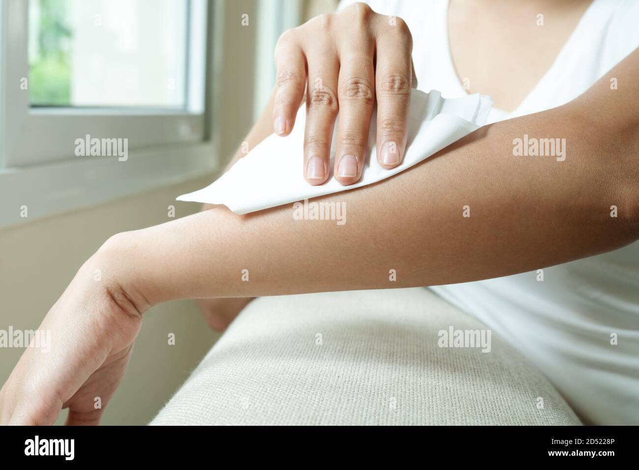 Woman cleaning her arm with white soft tissue paper Stock Photo - Alamy
