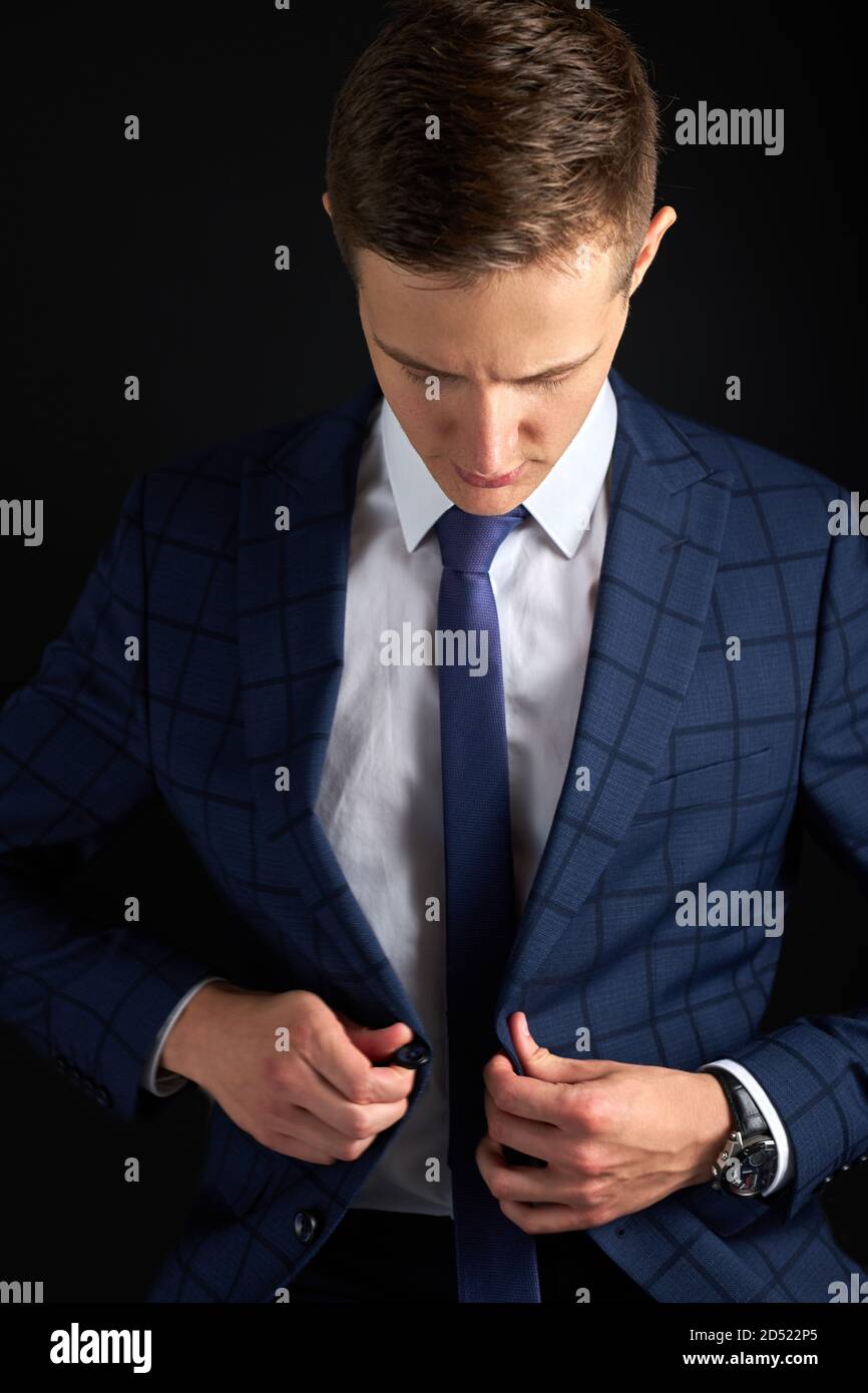 rich young male in classic formal suit or tux fixing button on jacket ...