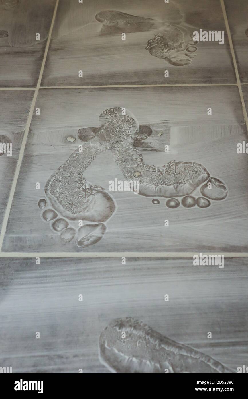 multiple footprints coming and going through grout Stock Photo - Alamy