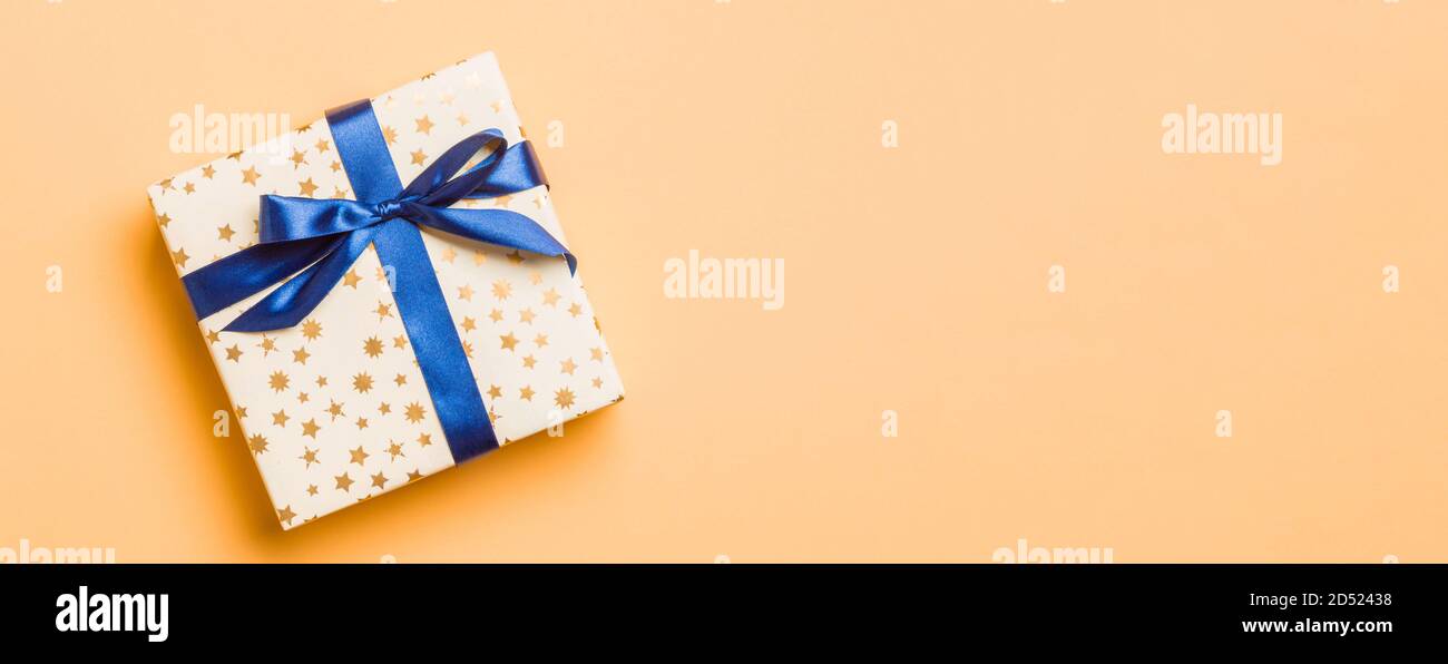 Top view Christmas present box with blue bow on orange background with ...