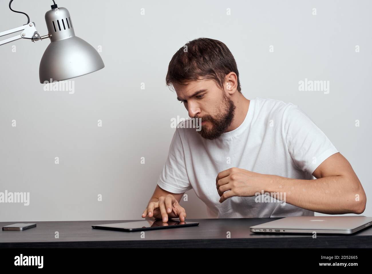 A man with a tablet at the table gestures with his hands on a light ...