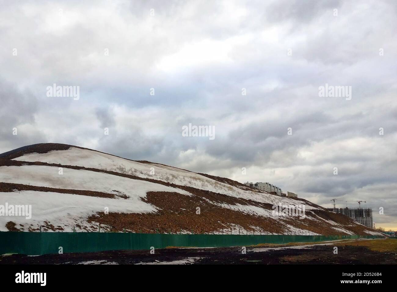 Dump on the background of the city under construction in winter. A ...
