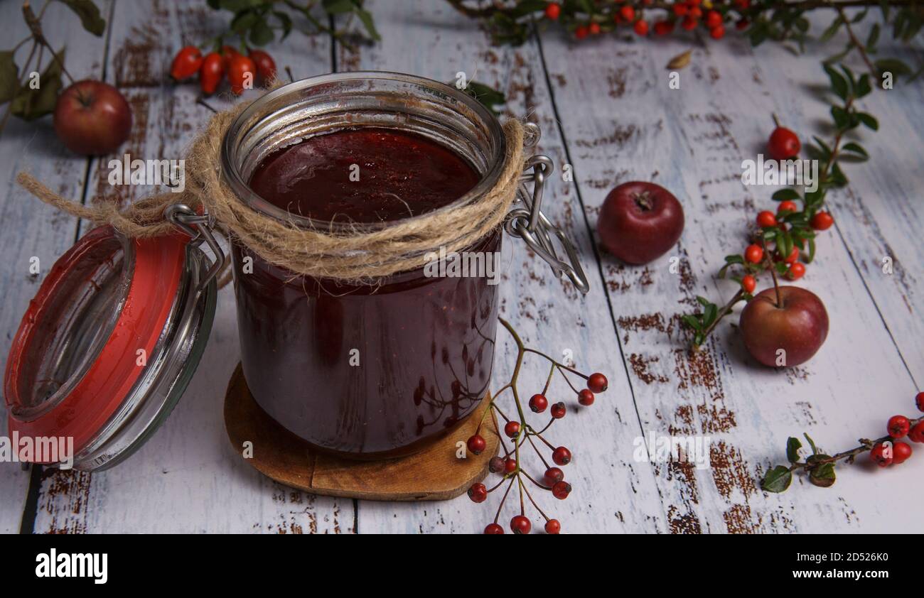 jar of homemade strawberry jam in a glass jar stands on a white wooden ...