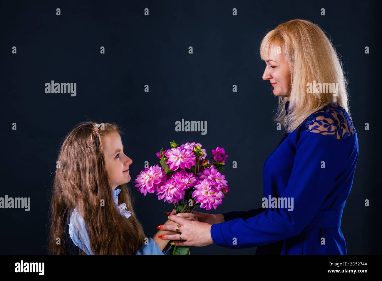 Little girl gives mom flowers and wishes her with mothers day. Maybe ...
