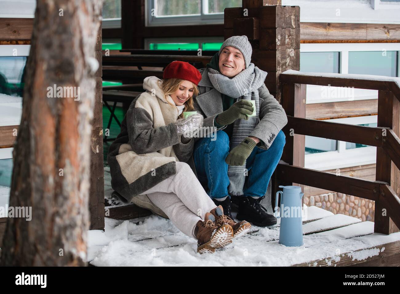 Beautiful blonde and cute man bask in the gazebo, drink hot drinks ...