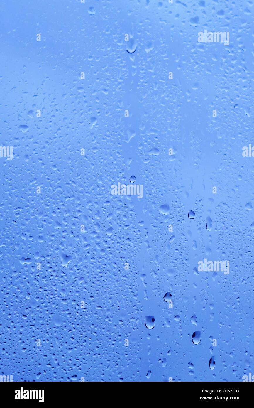 Autumn window with the texture of water drops against a cloudy blue sky ...
