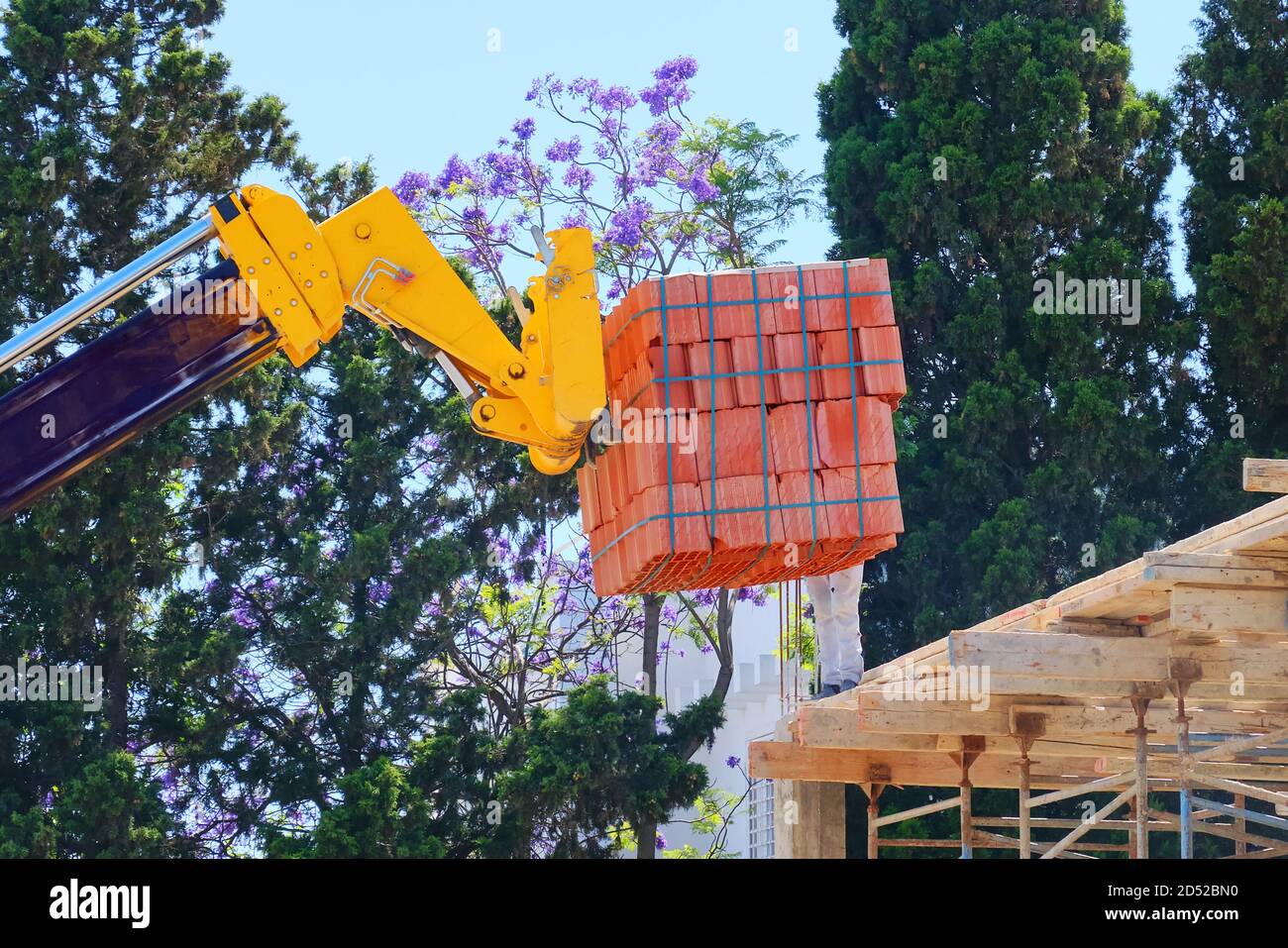 Supply packing bricks crane on the unfinished building Stock Photo - Alamy