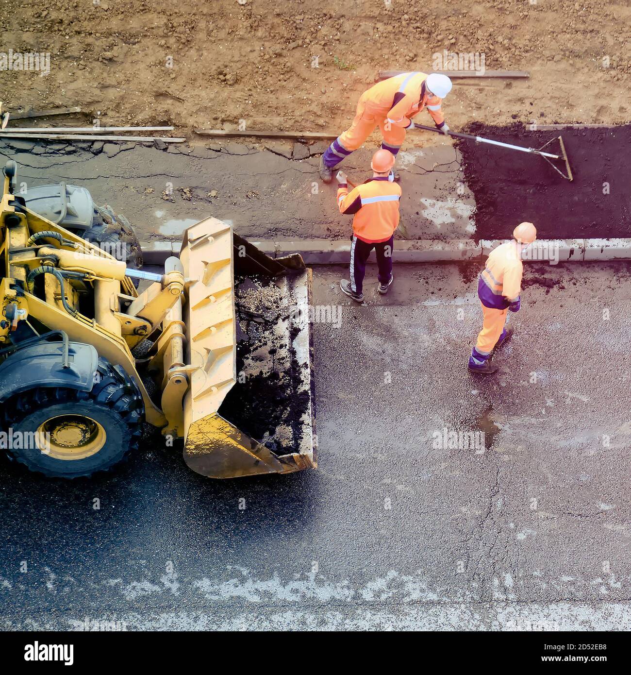 Road workers level the asphalt on the ground with shovels and lay it ...