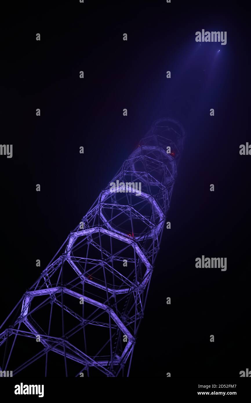 dimly lit lattice TV tower with a top hiding in the night fog Stock ...