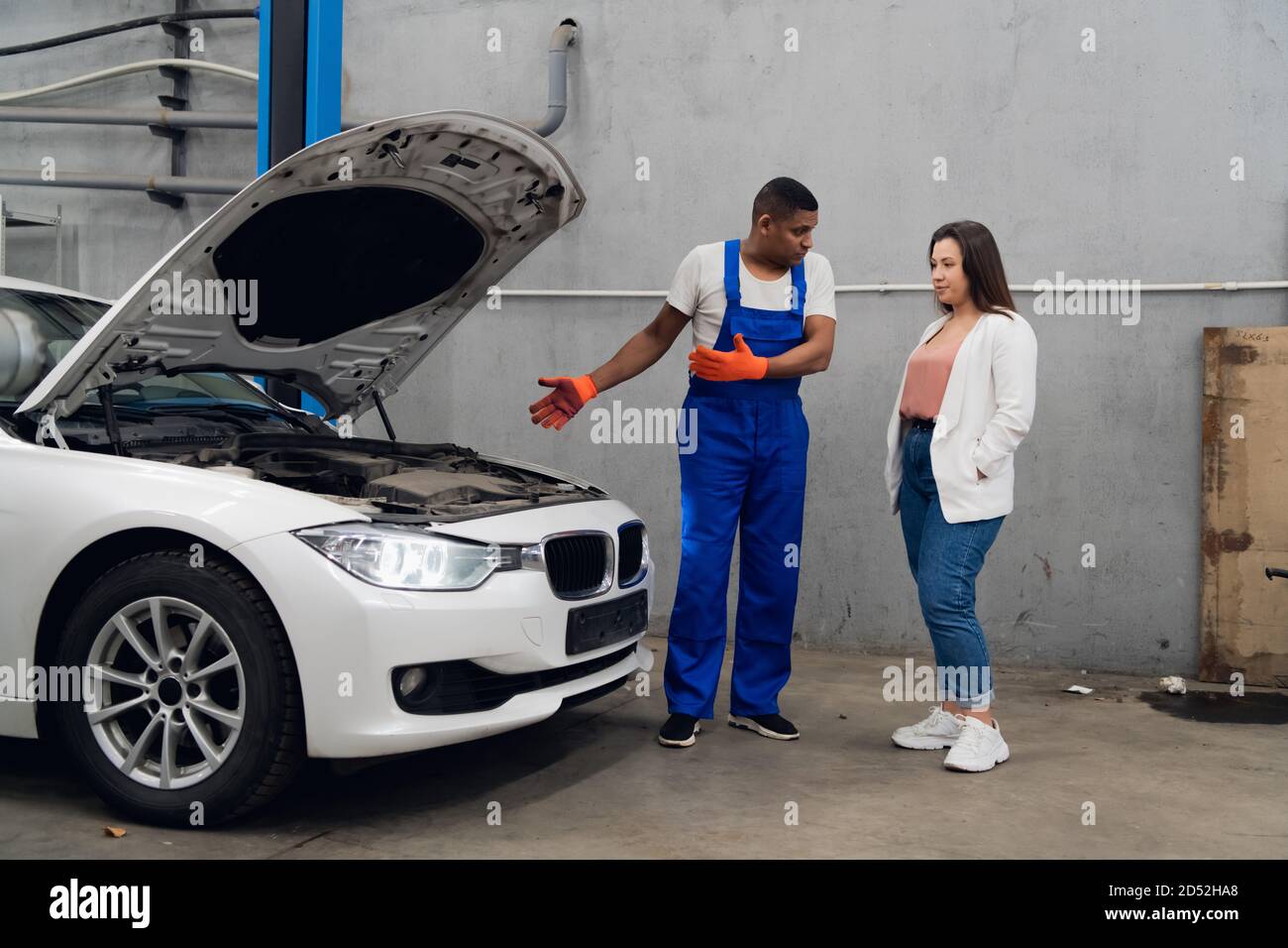 Repairer and client discuss car engine repair Stock Photo - Alamy