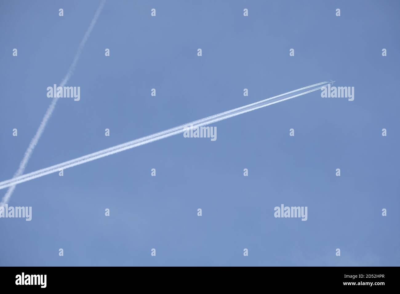 Long white planes traces crossing in the clear cloudless blue sky and ...