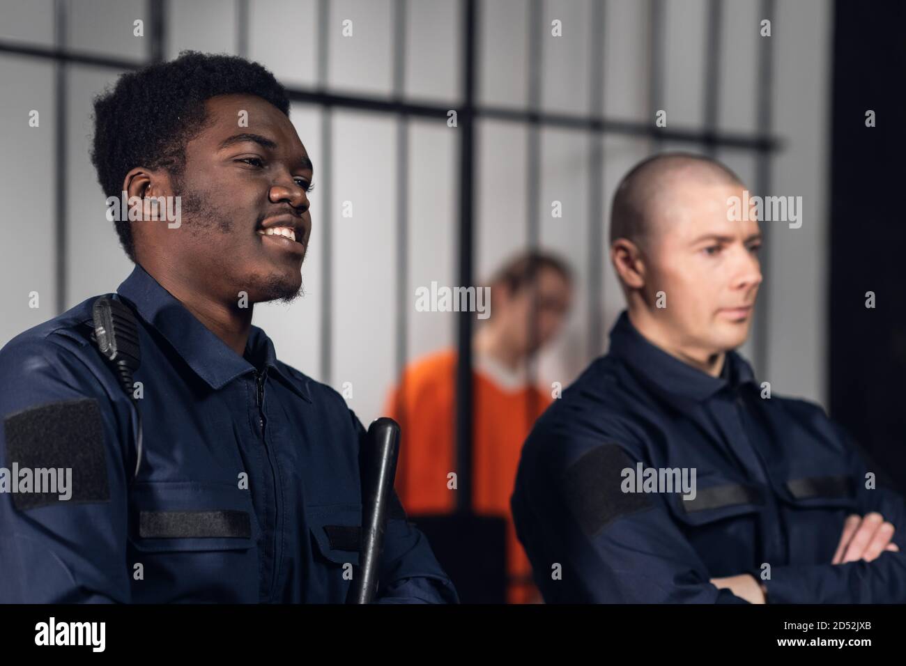 Prison guards smile as they stand with batons near cells with dangerous ...