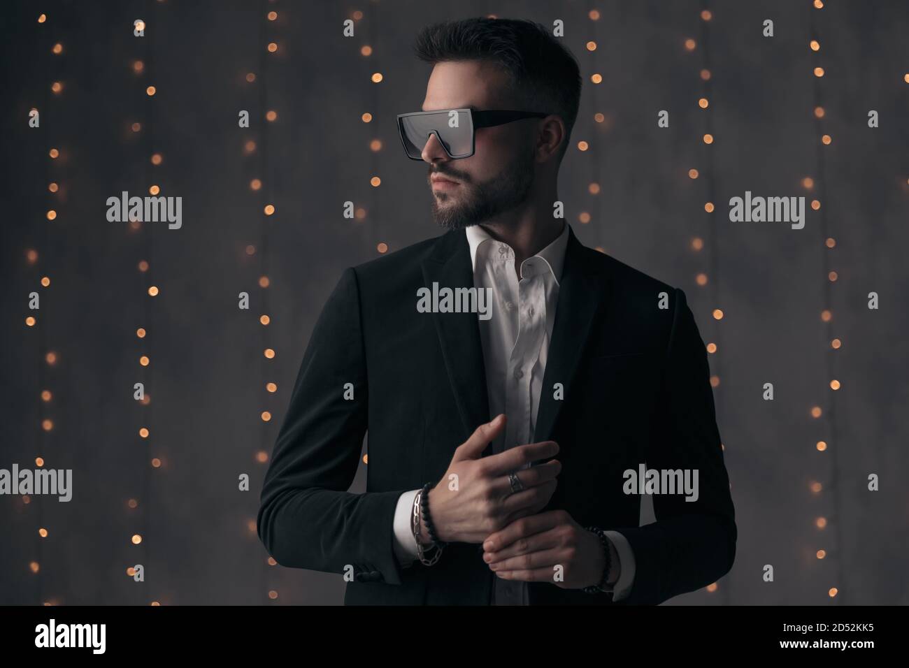 Determined fashion model adjusting his rings and looking away while ...