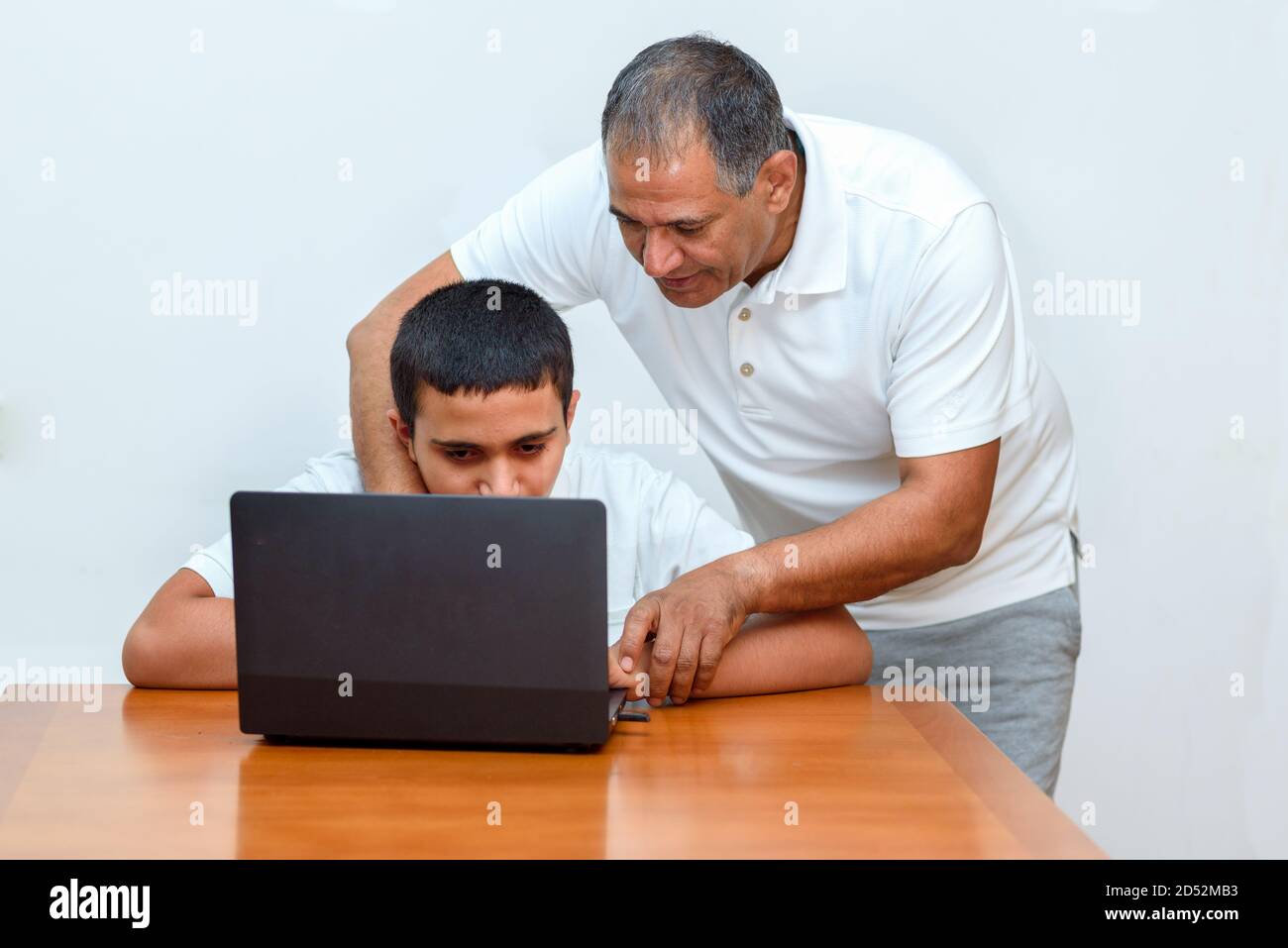 Senior Father and teenage son using laptop. Boy and dad sitting at home ...