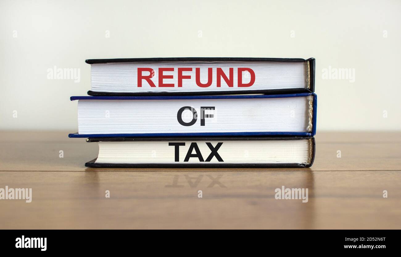 Books with text 'refund of tax' on beautiful wooden table. White ...