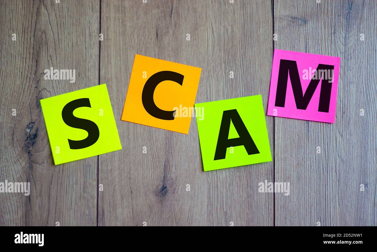 Concept word 'scam' on colored paper on a beautiful wooden background ...