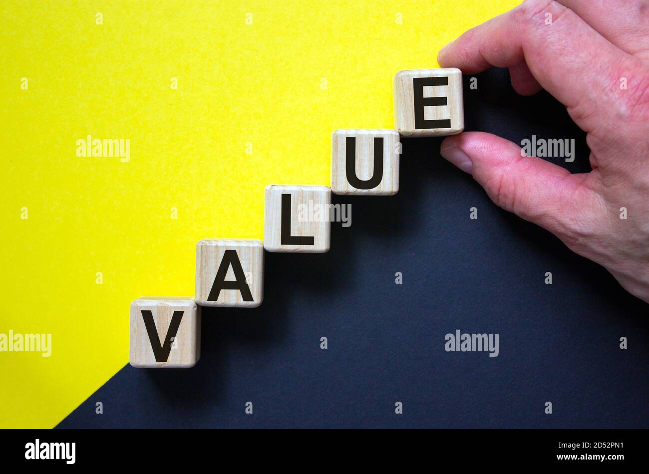 Wood cubes with word 'value' stacking as step stair on paper yellow and black background, copy ...