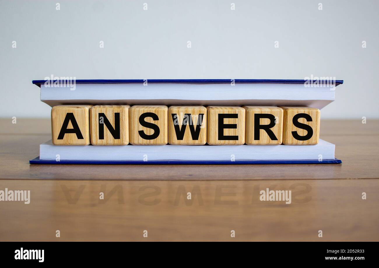 Concept word 'answers' on wooden cubes between pages of a book on a ...
